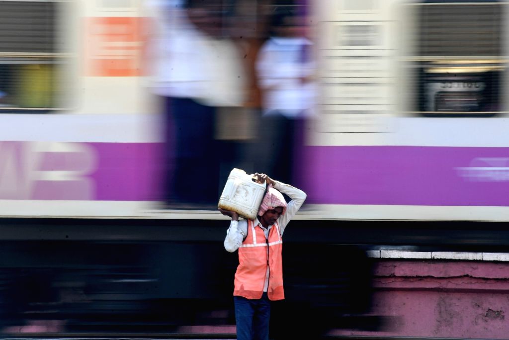 Mumbai : A worker carries a water container at a railway track during ...