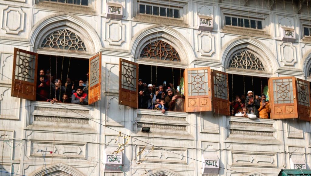 Muslim devotees click photos from windows as a priest (unseen) display ...