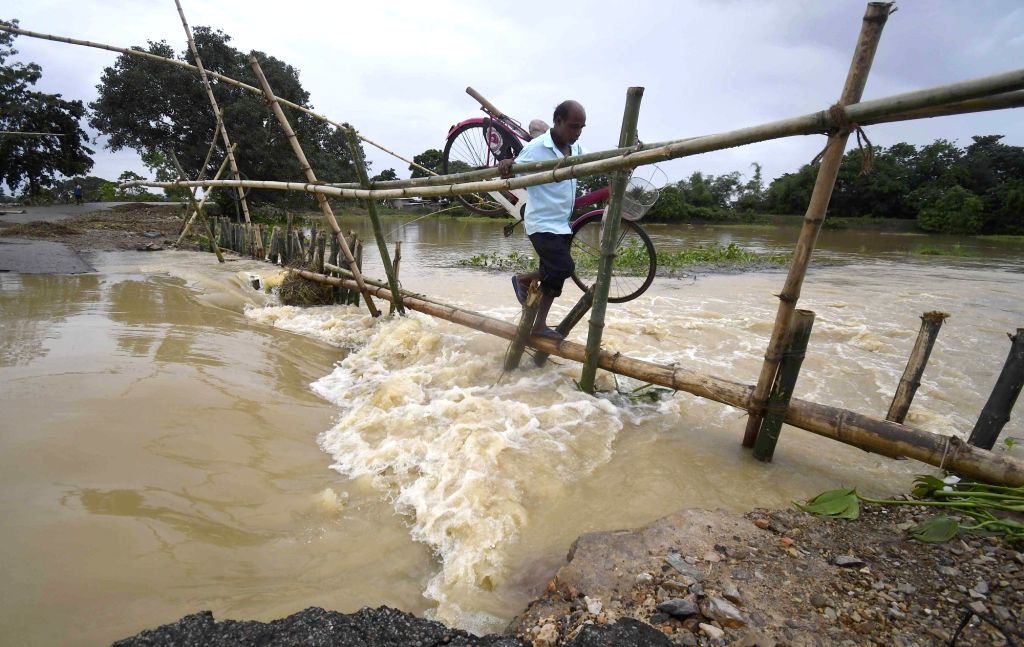 Villagers make a temporary bamboo bridge after a portion of a road was ...