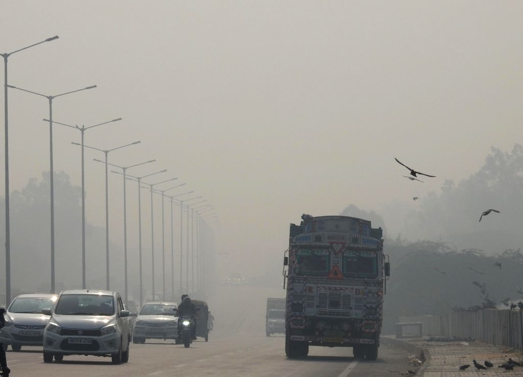 : New Delhi :Commuters drive amidst morning haze and toxic smog.