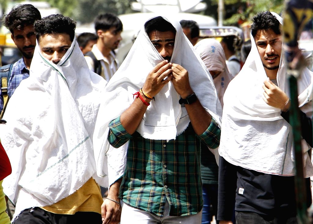 New Delhi : Men wear a scarf to cover themselves from scorching heat on ...