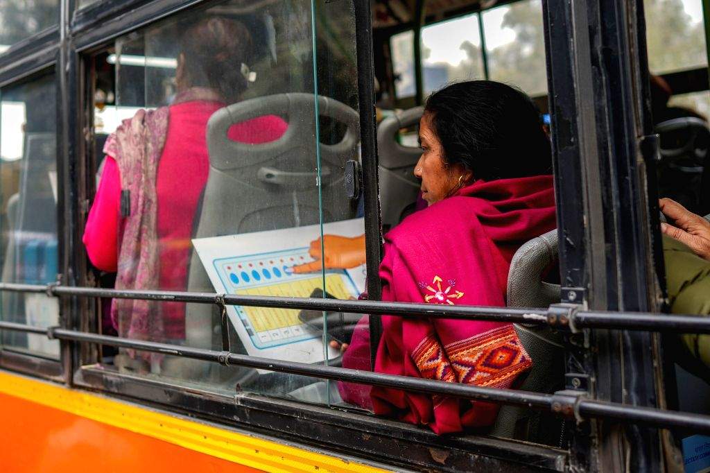 Polling officials travel in a bus with EVMs and election materials as ...