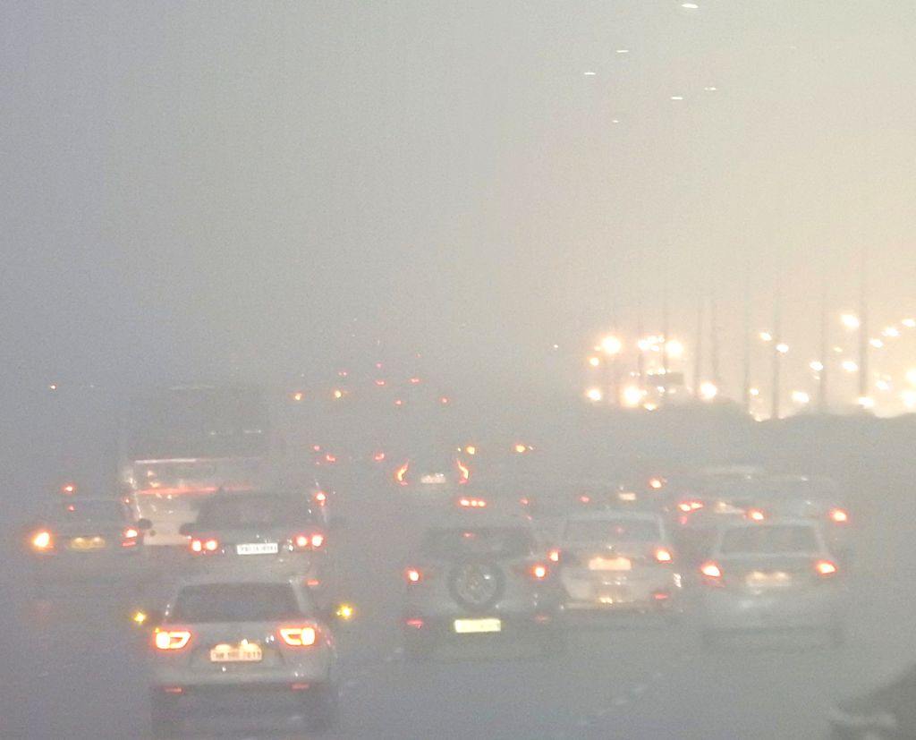 New Delhi : Vehicles move on road during smog and foggy winter morning