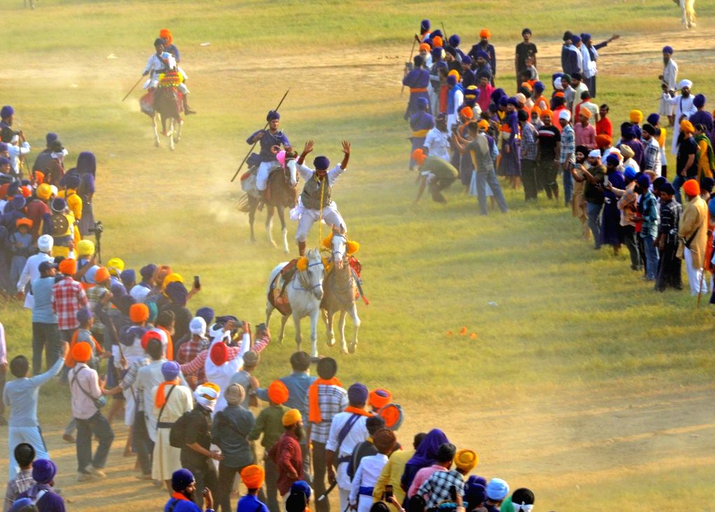 Nihang Sikh warriors ride horses standing on their backs during a Fateh ...