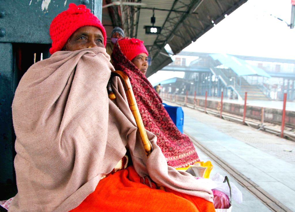 : Haridwar: Passengers wearing warm clothes wait for a train at a ...
