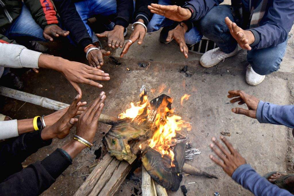 Patna : People sit around a bonfire to warm themselves on a cold winter day