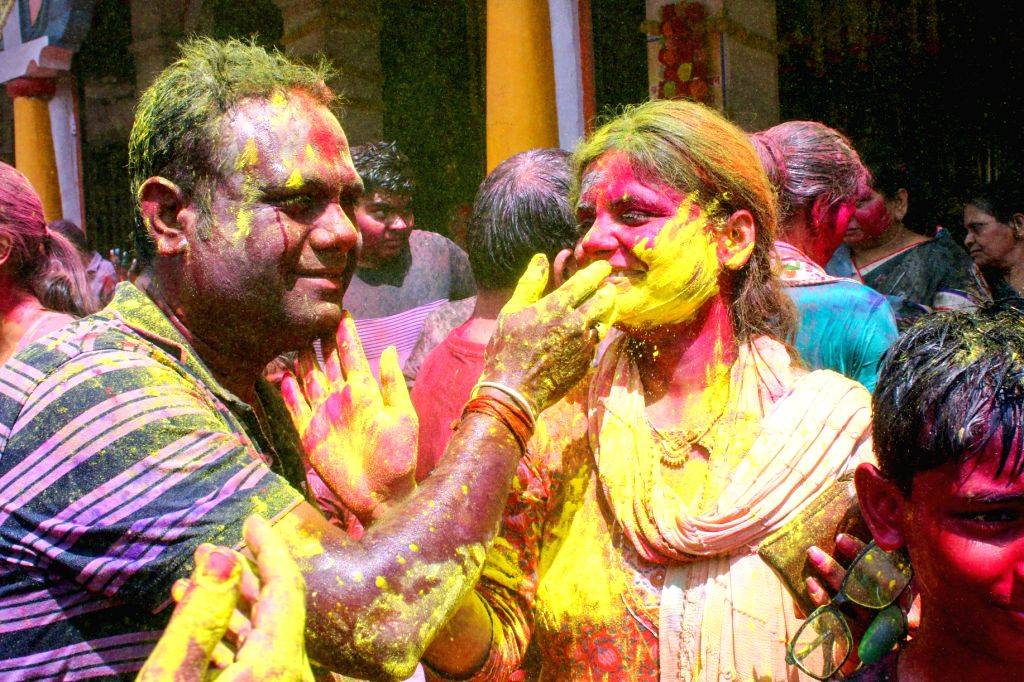 People cheer as colored powder and water are sprayed on them during ...