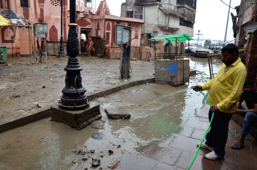 People clean a muddy area after the water level of river Ganga decreases
