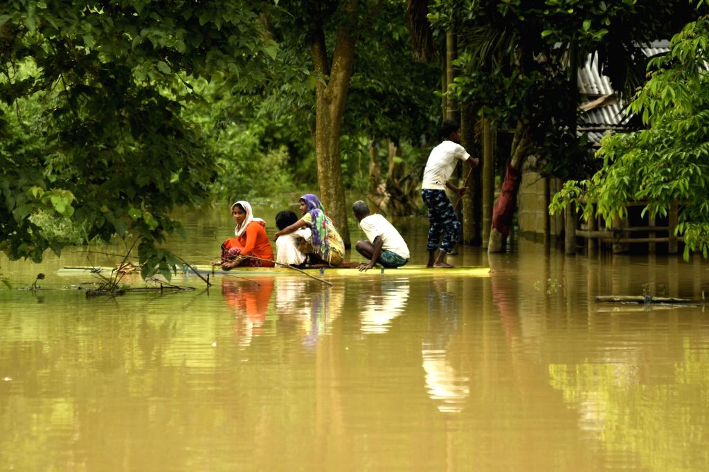 People make their way on a raft past homes in a flooded area after ...
