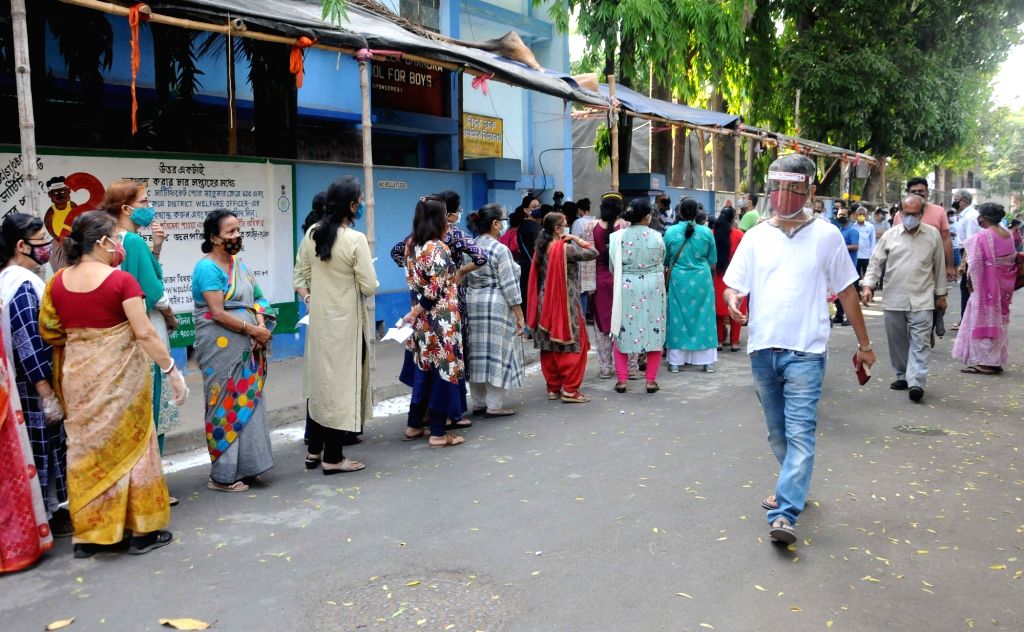 People stand in a queue at a polling station to cast their vote during ...