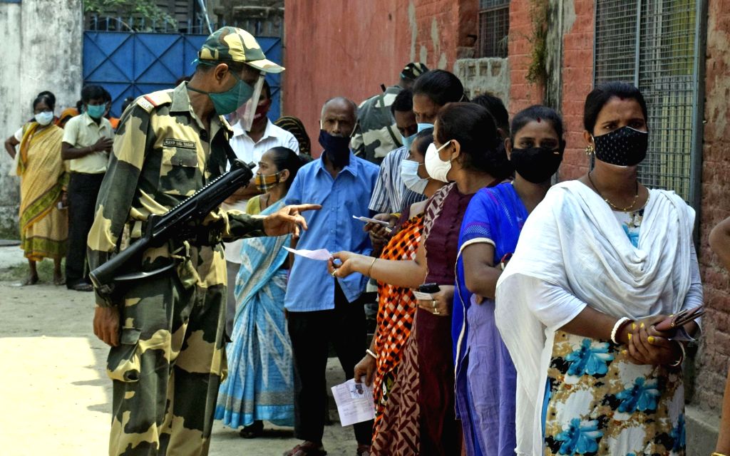People stand in a queue at a polling station to cast their vote at ...