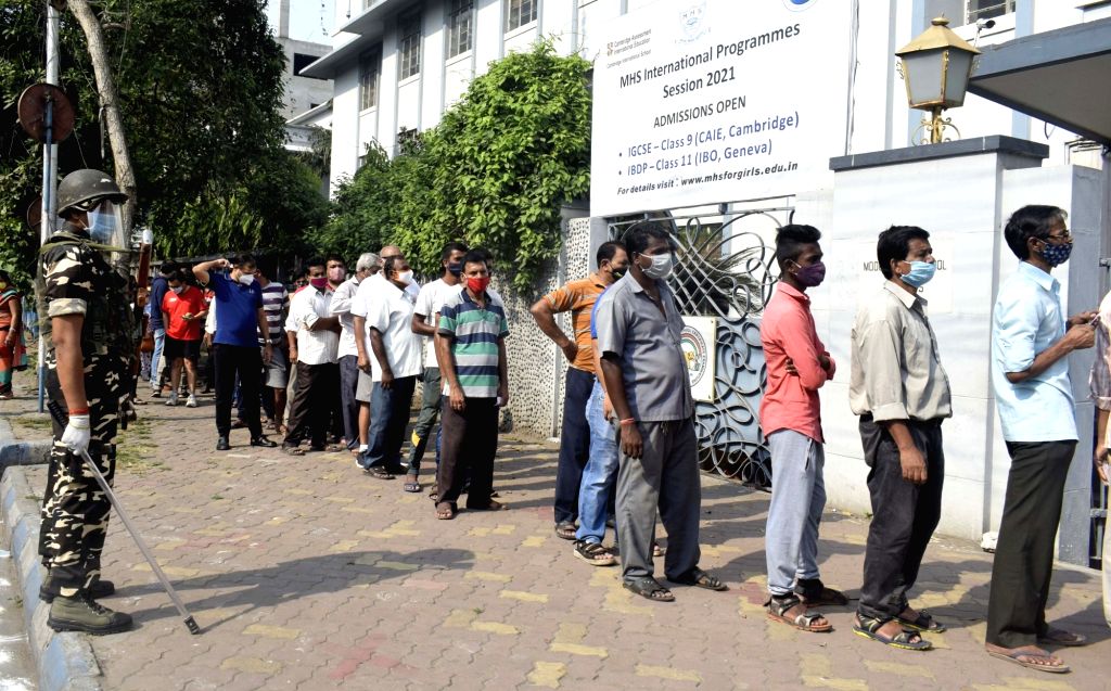 Kolkata : People stand in a queue at a polling station to cast their ...