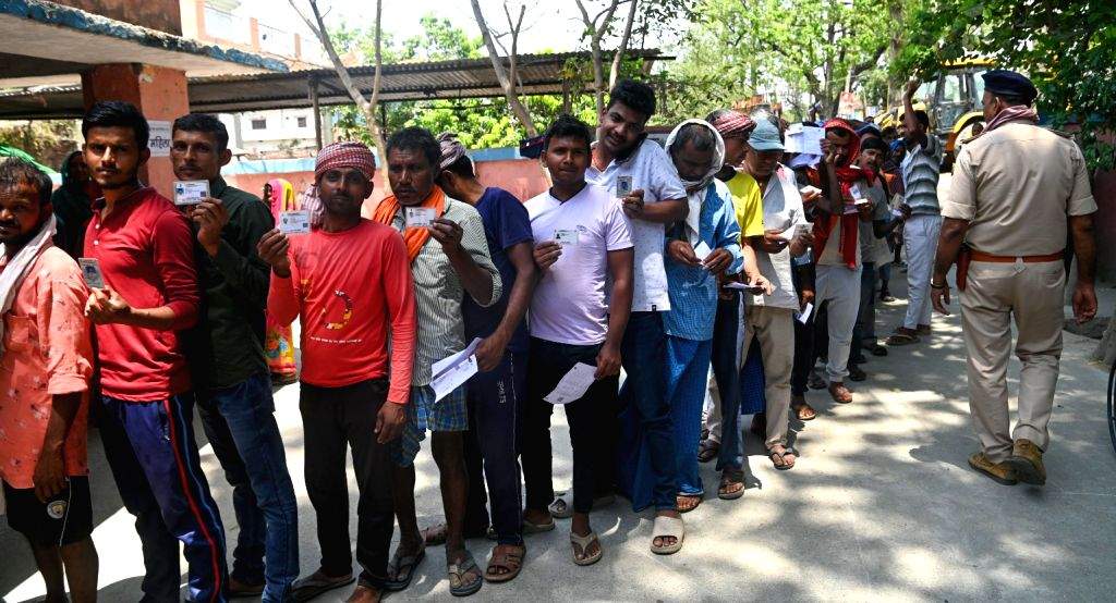 People stand in a queue to cast their votes at a polling booth during ...