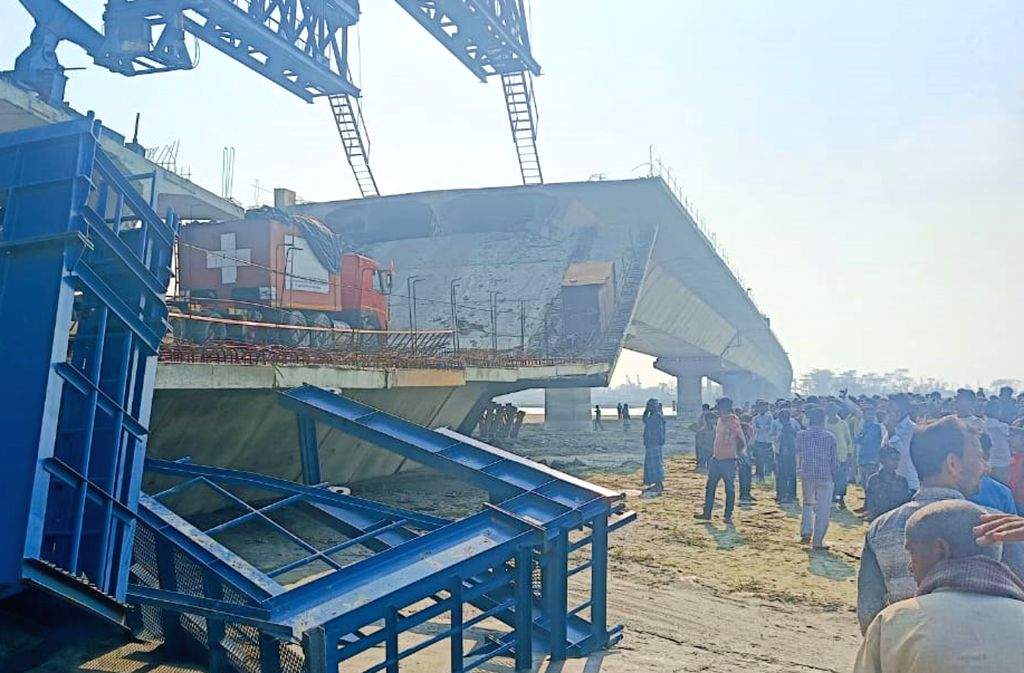 People stand near the collapsed portion of an under-construction bridge ...