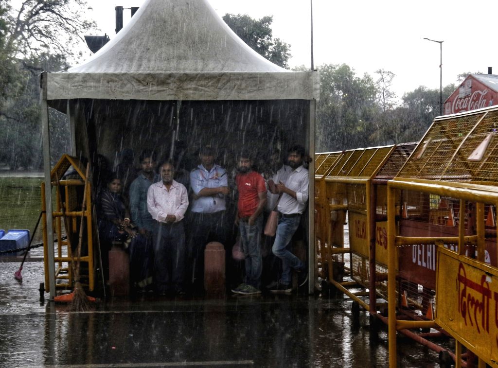 People take shelter amid rain at India Gate