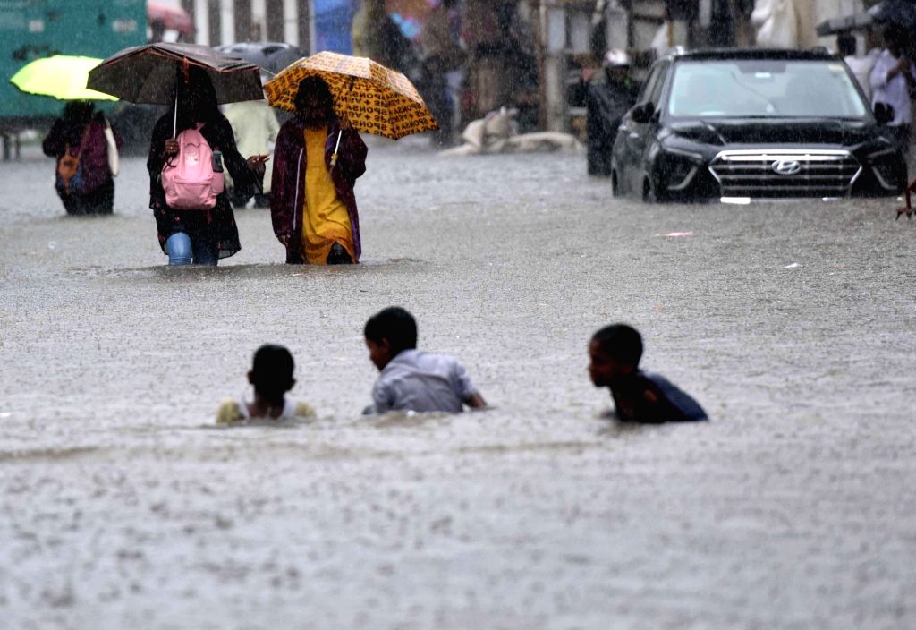 People wade past a waterlogged road during heavy rainfall.