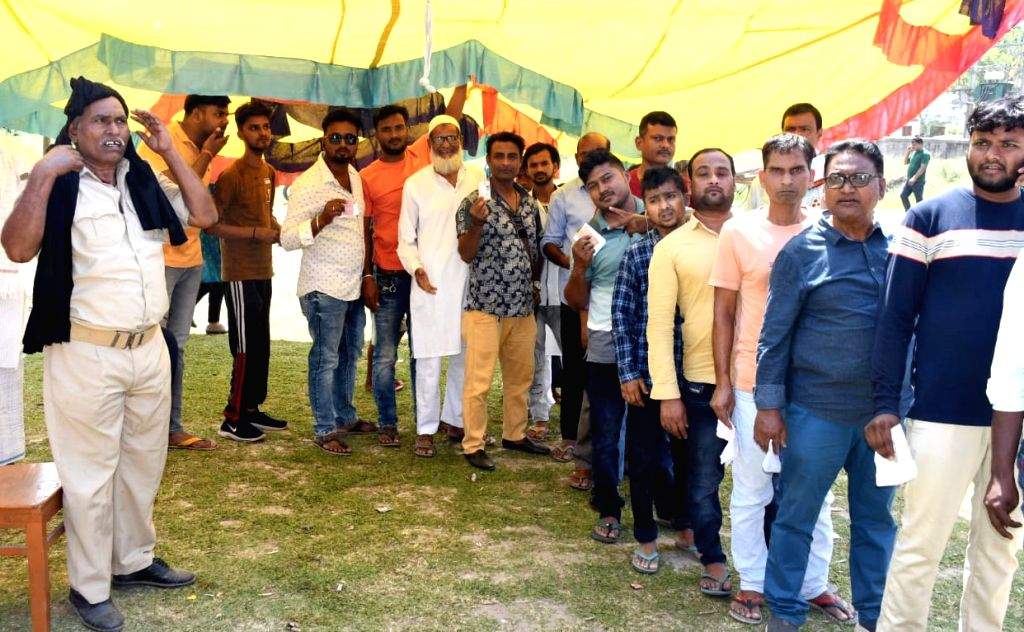 People wait in a queue to cast their votes for the 2nd phase of Lok ...