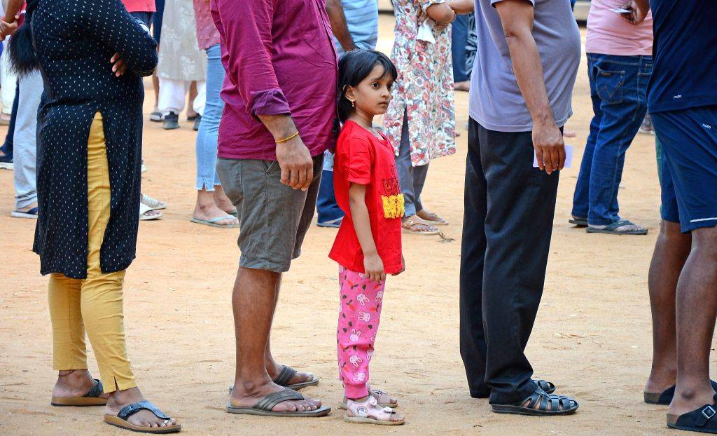 People wait in a queue to cast their votes for the 2nd phase of Lok ...