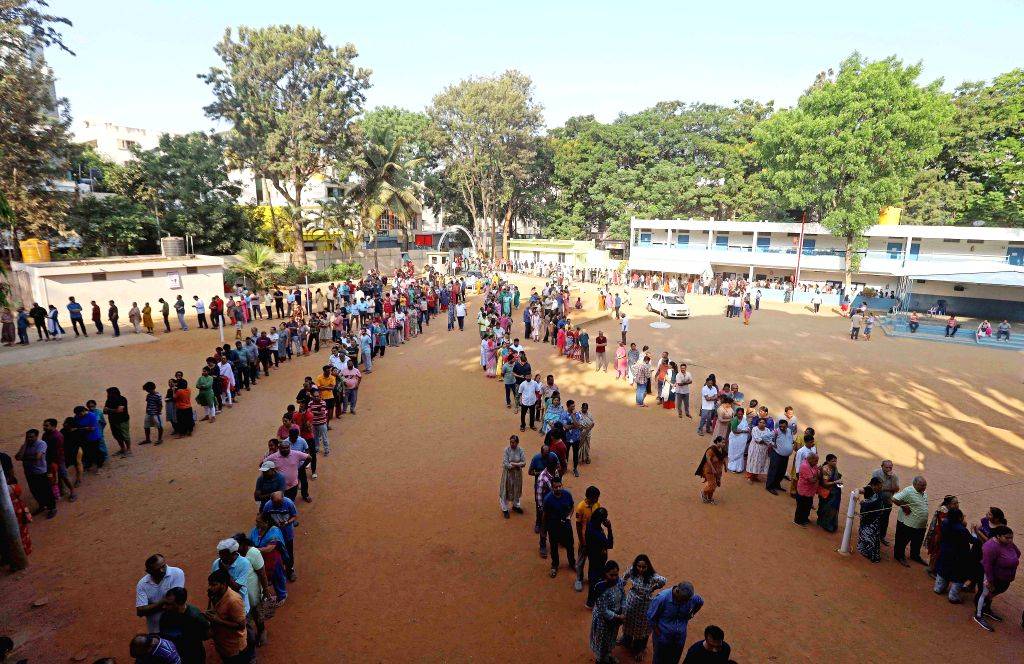 People wait in a queue to cast their votes for the 2nd phase of Lok ...