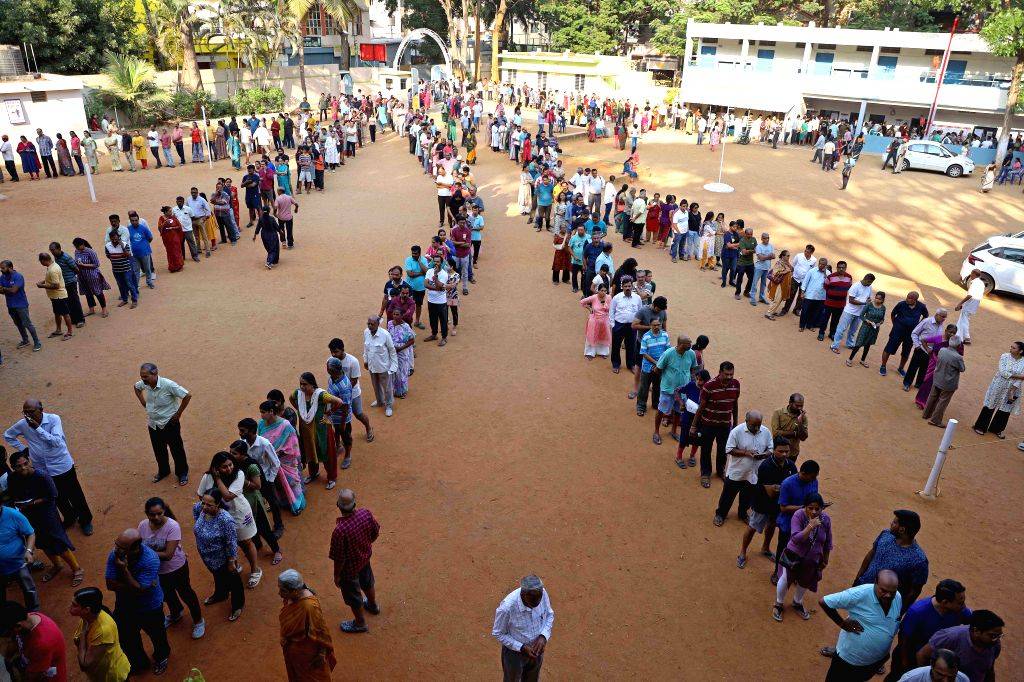 People wait in a queue to cast their votes for the 2nd phase of Lok ...