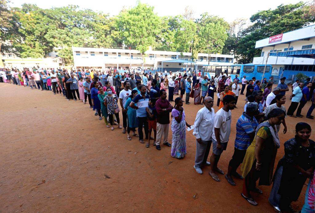 People wait in a queue to cast their votes for the 2nd phase of Lok ...