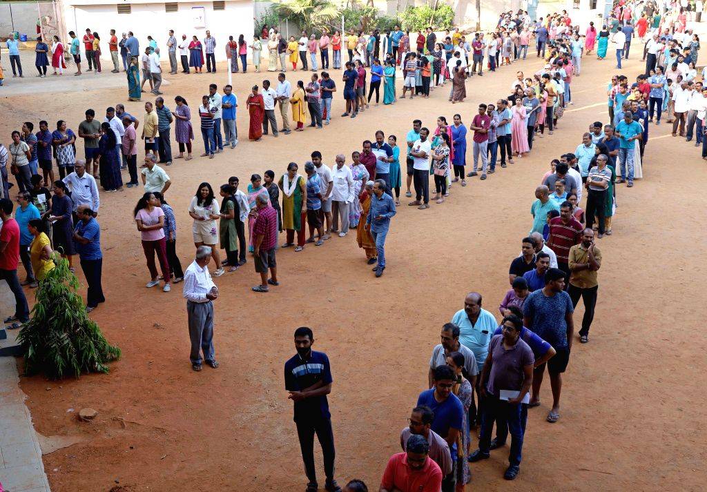 People wait in a queue to cast their votes for the 2nd phase of Lok ...