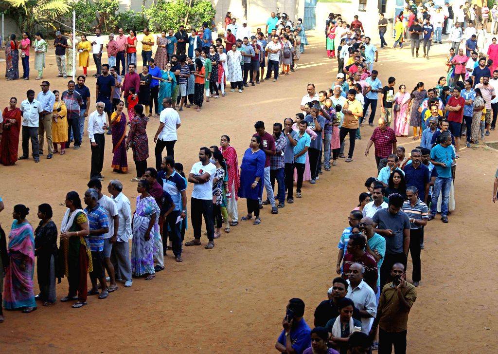 People wait in a queue to cast their votes for the 2nd phase of Lok ...