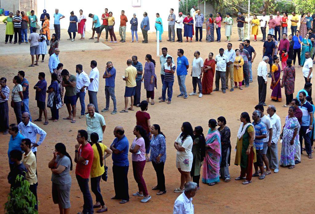 People wait in a queue to cast their votes for the 2nd phase of Lok ...