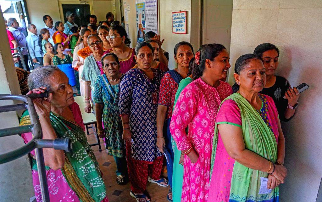 People wait in queues to cast their votes at a polling station during ...