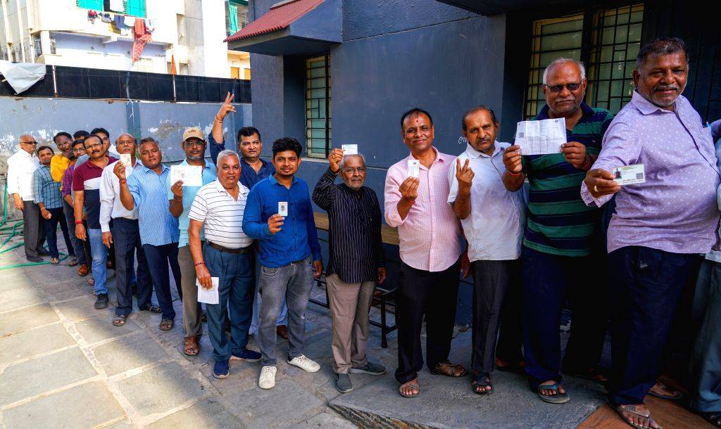 People wait in queues to cast their votes at a polling station during ...