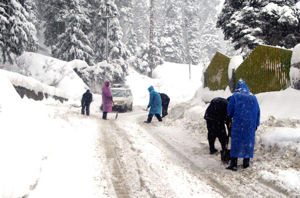 People walk on a snow-covered road as heavy snowfall