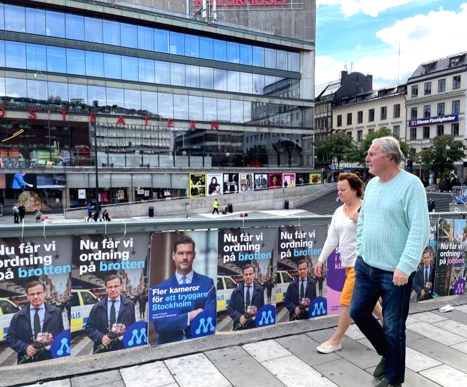 People walk past election campaign posters in Stockholm