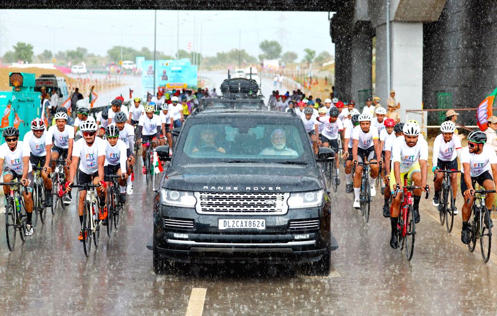 PM Modi's convoy rides along a platoon of cyclists during the roadshow ...