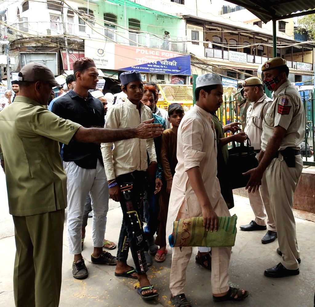 Police personnel check Muslim people at the entrance of Jama Masjid