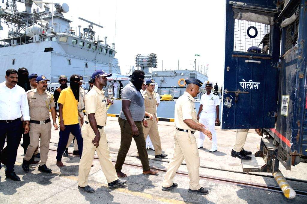 Police take away nine pirates who were handed over by the Indian Navy
