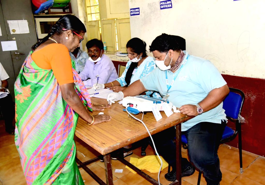 Polling official administers indelible ink to a voter, at a polling ...