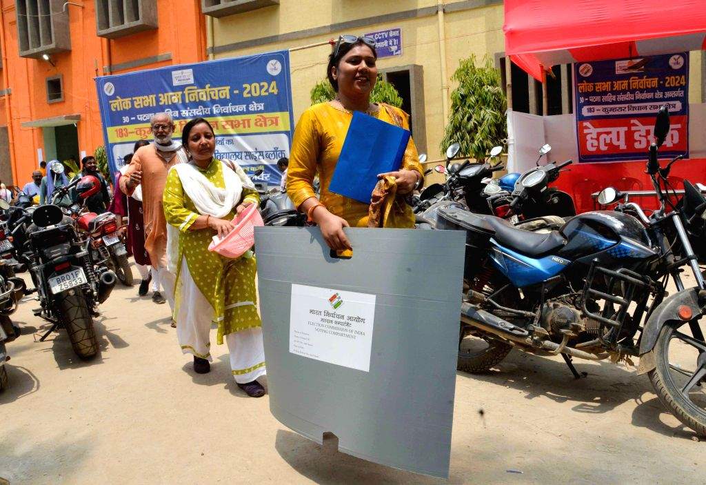 Polling officials carry Electronic Voting Machines (EVMs) and other ...