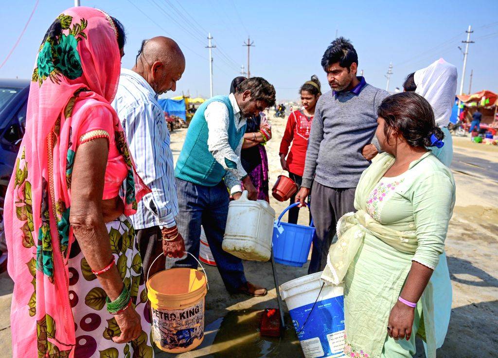 Devotees stand in a queue to take water from a roadside tap