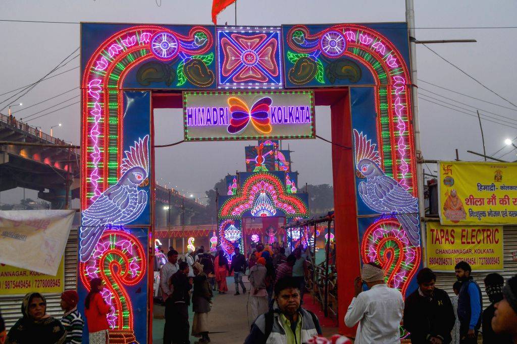 Visitors walk through an illuminated entry gate at the Maha Kumbh Mela 2025