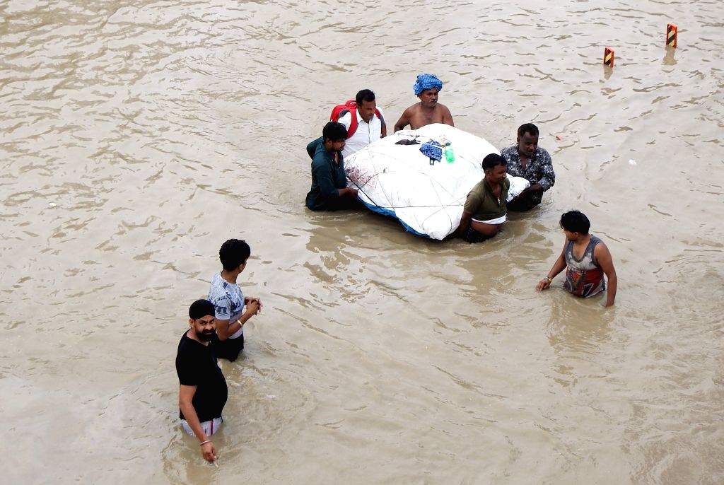 Residents with their belongings wade through a flood-affected area