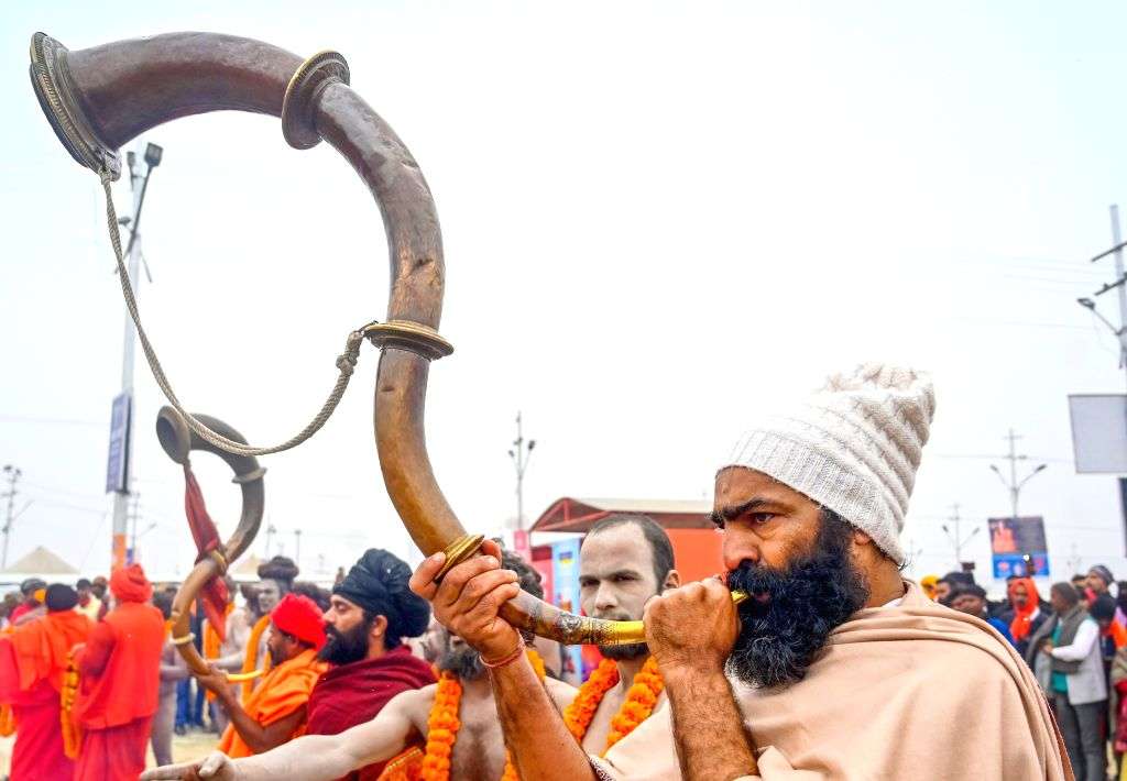 Sadhus blow traditional horns during a ritual at the Triveni Sangam