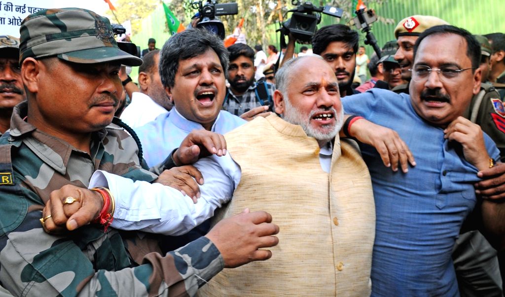 Security personnel detain a BJP worker during their demonstration