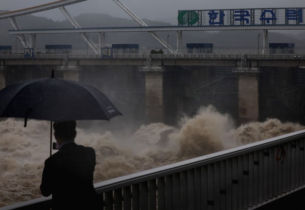 Seoul :A man photographs water pouring out of floodgates at Paldang Dam ...