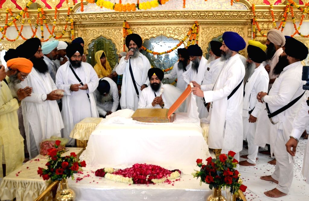 Sikh priests display a copy of Guru Granth Sahib that is said to have ...