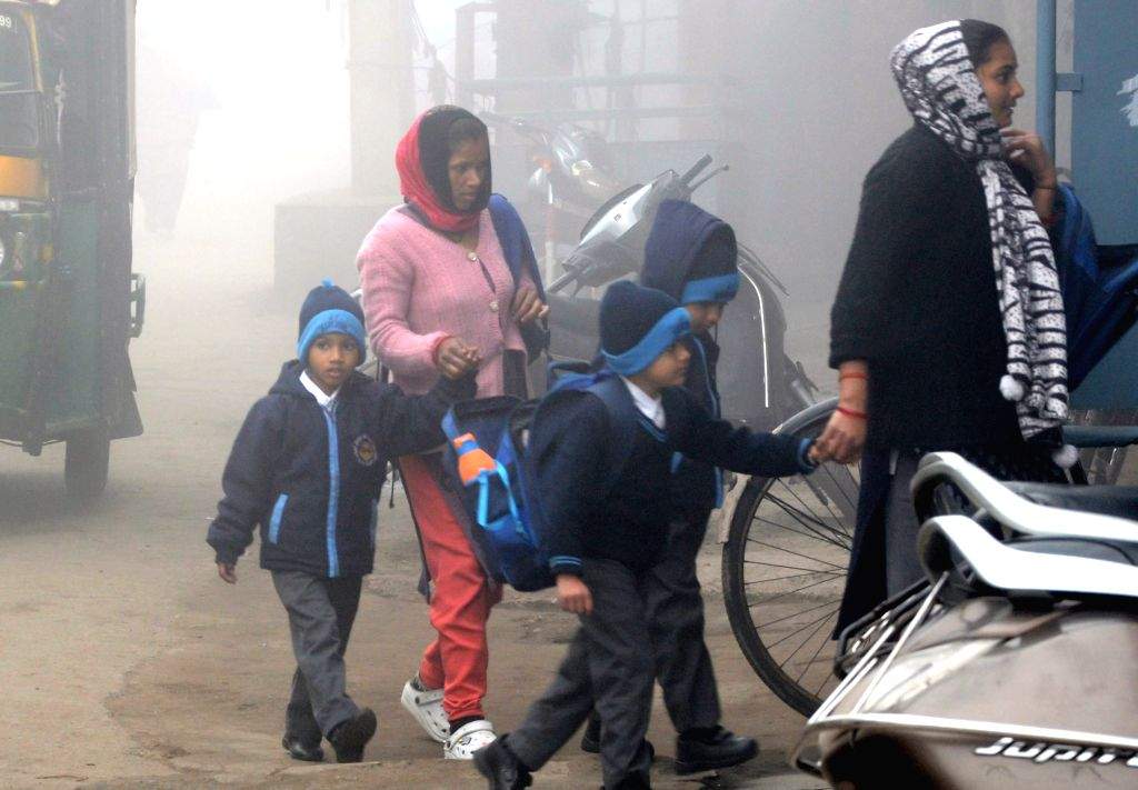 Students walk to school through a foggy morning