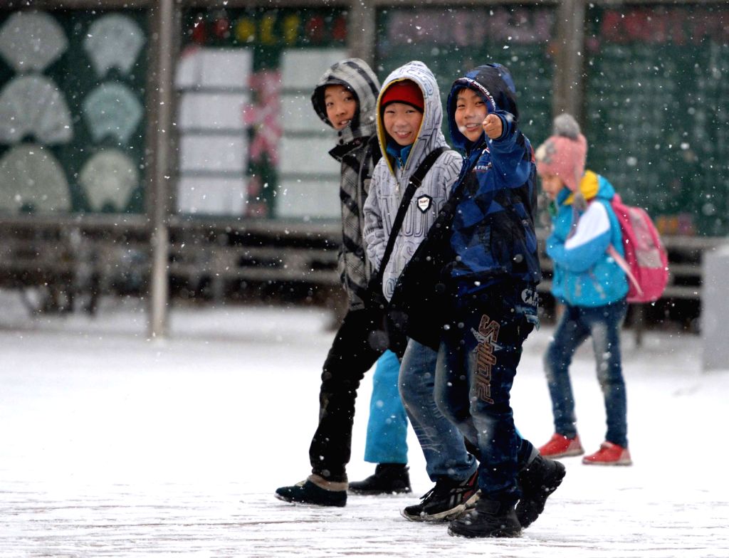 Pupils walk in snow on their way to school in Suibin County