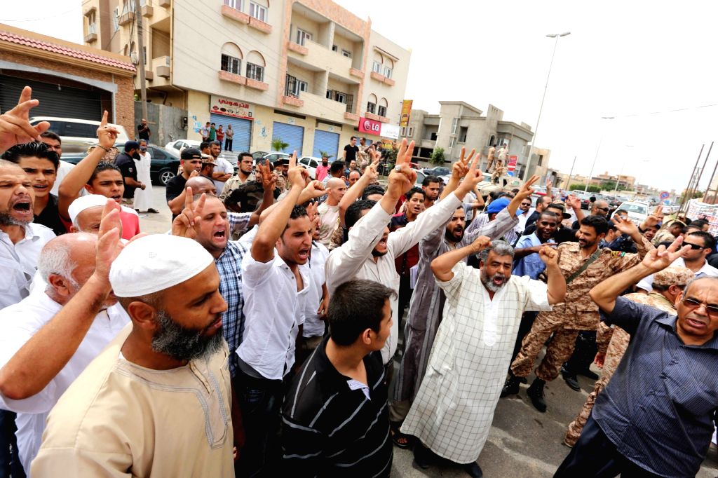 Libyan citizens and members of the security forces shout slogans