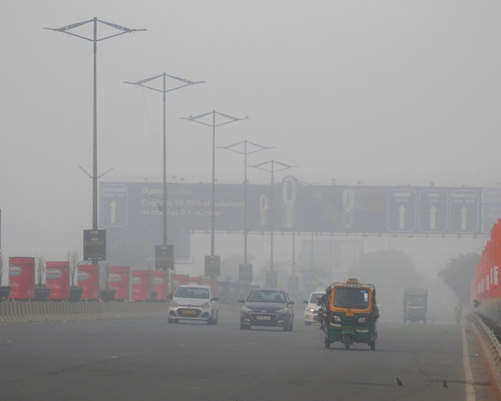 Vehicles ply on a road amid low visibility due to thick layer of smog