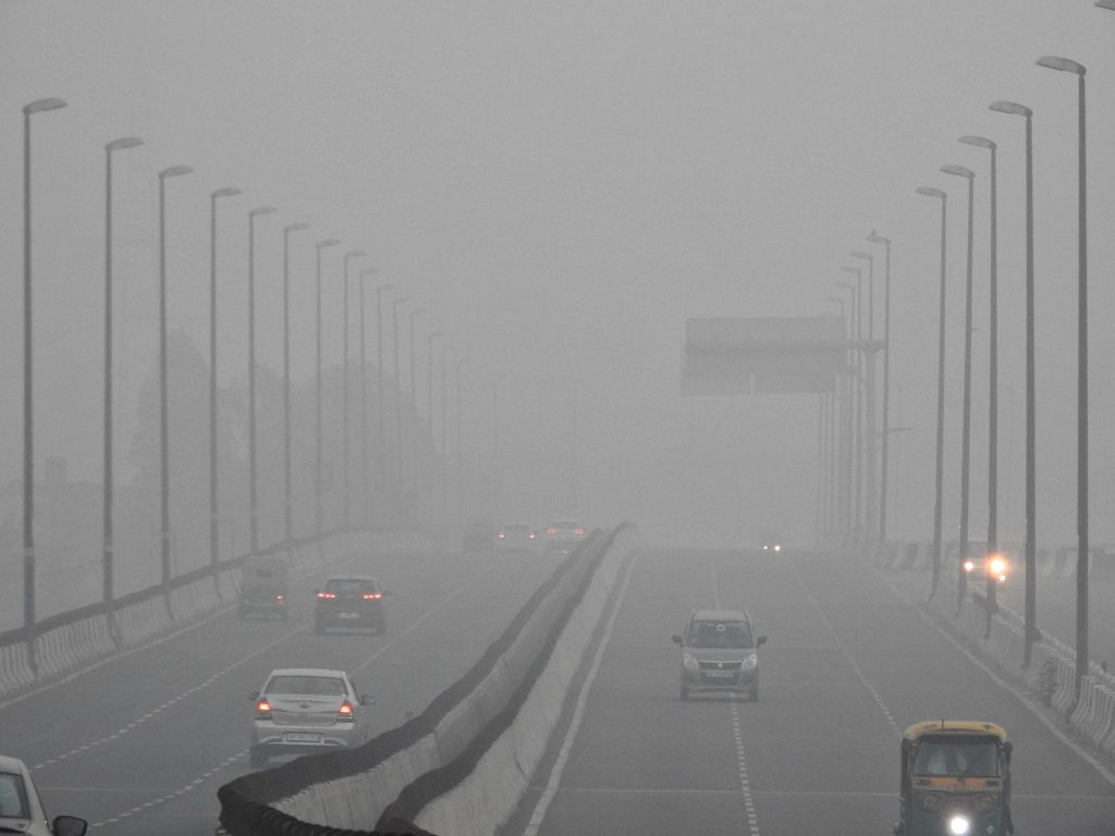 Vehicles ply on a road amid low visibility due to thick layer of smog