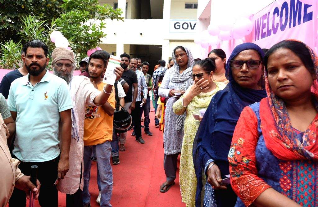 Voters stand in the queue to cast their votes, at a polling booth ...